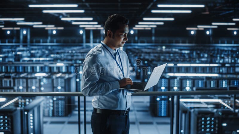 Portrait of it Specialist Uses Laptop in Data Center. Server Farm Cloud ...