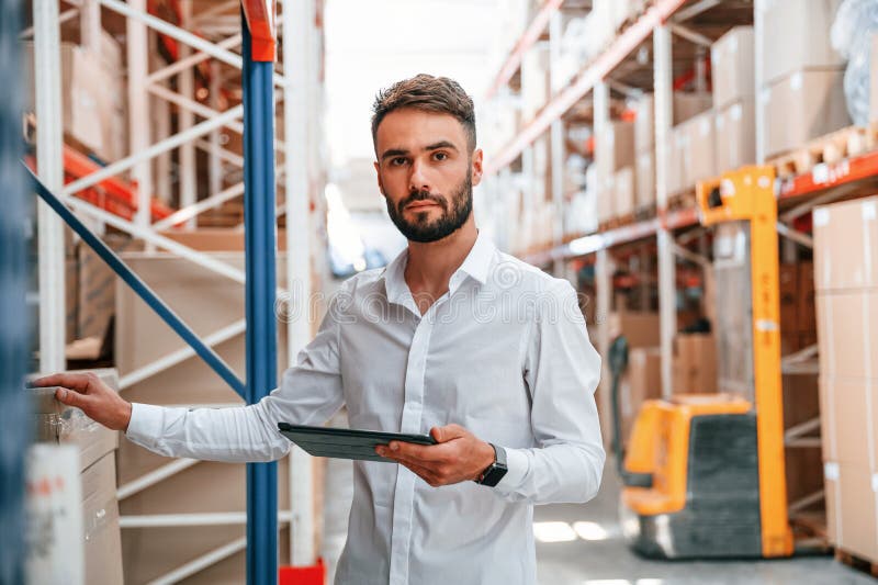 Portrait of Storage Worker that is in the Warehouse with Bunch of ...