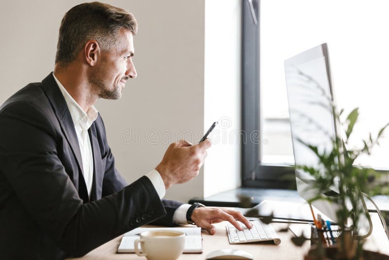 Portrait of Successful Businessman Using Mobile Phone while Working on ...
