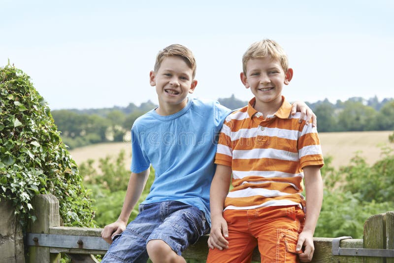 Portrait of Two Boys Sitting on Gate Together Stock Image - Image of ...