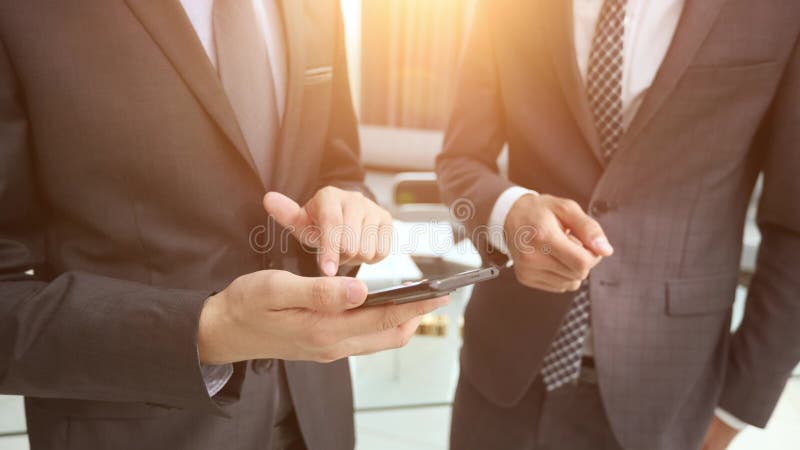 Two Businessmen Using Smartphone Stands in Office Corridor Stock ...