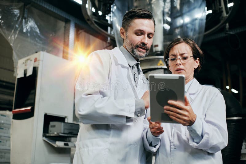 Two Engineers Working at the Factory Warehouse, Discussing Data on ...