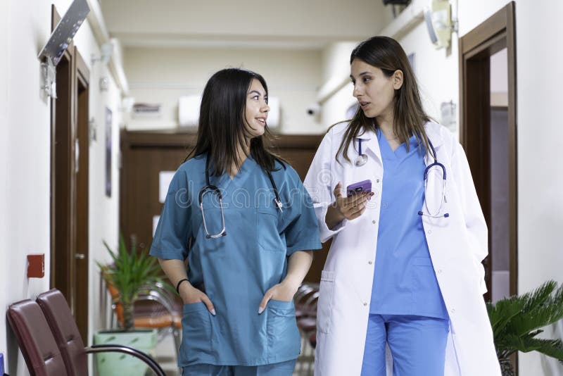 Portrait of Two Female Doctors Using Mobile Phone in Corridor at ...