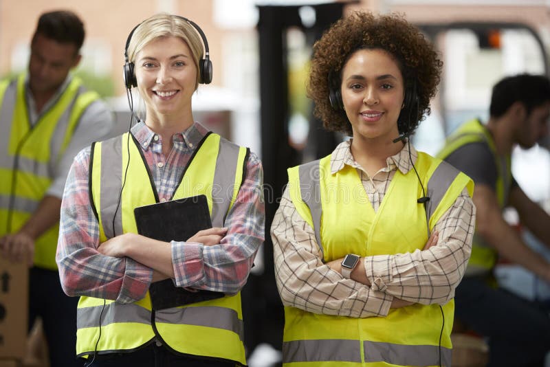 Portrait of Two Female Workers Using Headsets in Distribution Warehouse ...