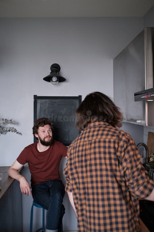 Two Men Talking in the Kitchen while One is Cooking Stock Image - Image ...