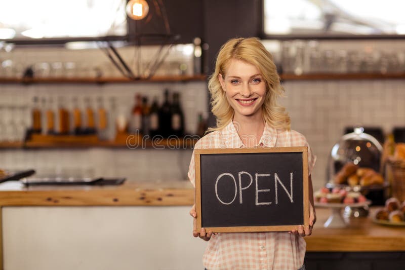 Female Standing Behind Counter at CafÃ© Holding OPEN Chalkboard Sign ...