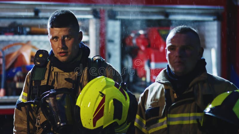 Portrait of Two Young Firefighters on the Rain in Front of Fire Engine ...