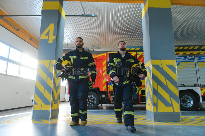Portrait of Two Young Firemen in Uniform Standing Inside the Fire ...