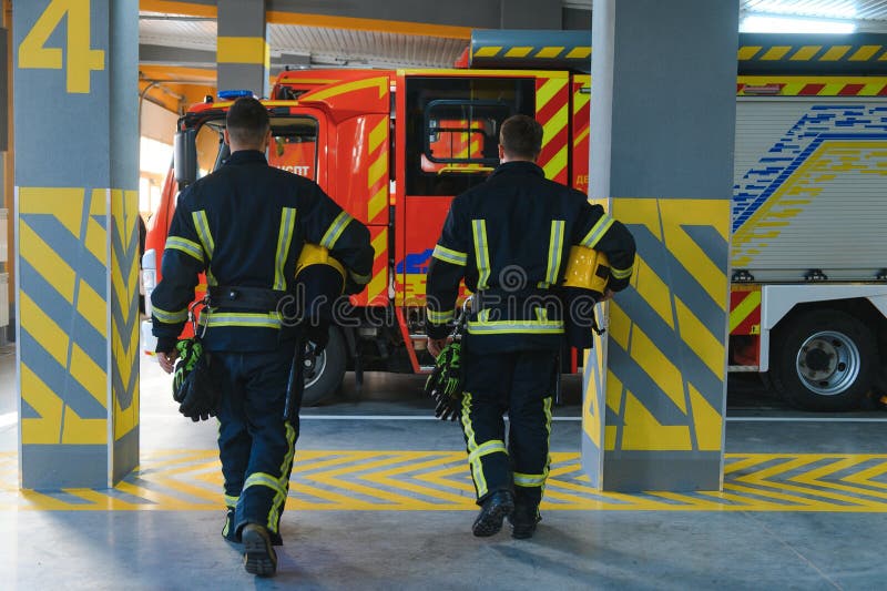 Portrait of Two Young Firemen in Uniform Standing Inside the Fire ...