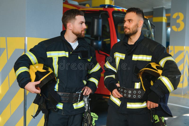 Portrait of Two Young Firemen in Uniform Standing Inside the Fire ...