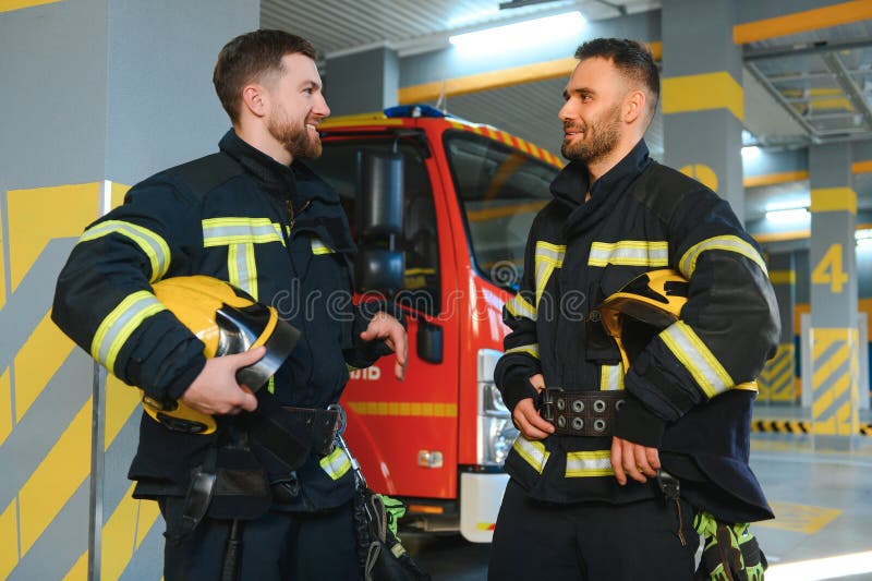 Portrait of Two Young Firemen in Uniform Standing Inside the Fire ...