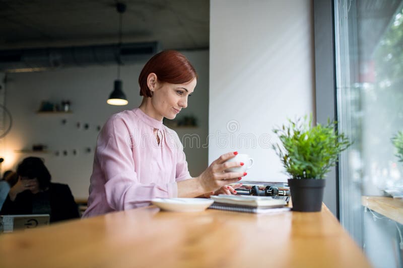 A Portrait of Woman with Coffee Sitting at the Table in a Cafe, Working ...
