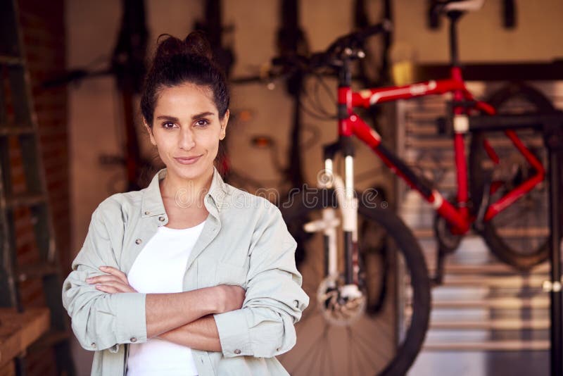 Portrait of Woman in Garage at Home with Cycle Hanging on Wall Behind ...