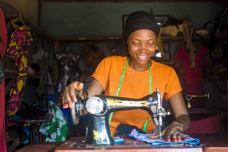 Portrait of a Young African Female Tailor Smiling while Working with ...