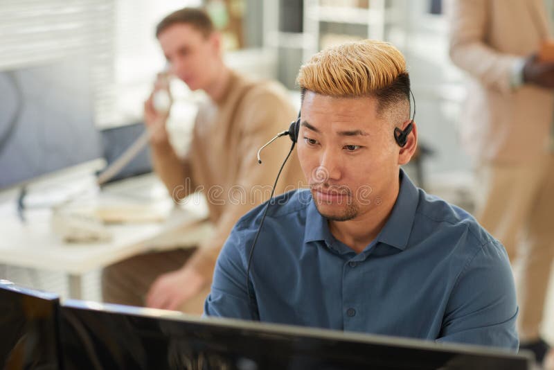 Young Asian Man Wearing Headset in Office and Looking at Computer ...