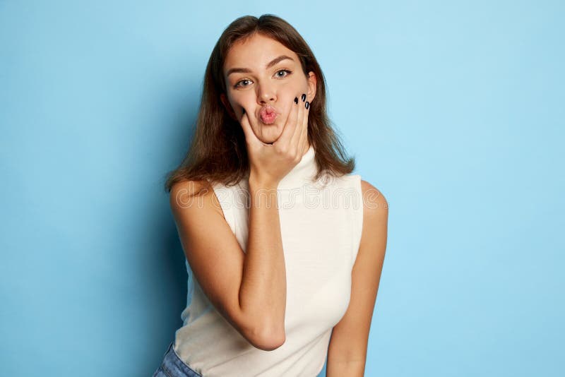 Portrait of Young Beautiful Woman Posing, Grimacing Isolated Over Blue ... Portrait of Young Beautiful Woman Posing, Grimacing Isolated Over Blue ...