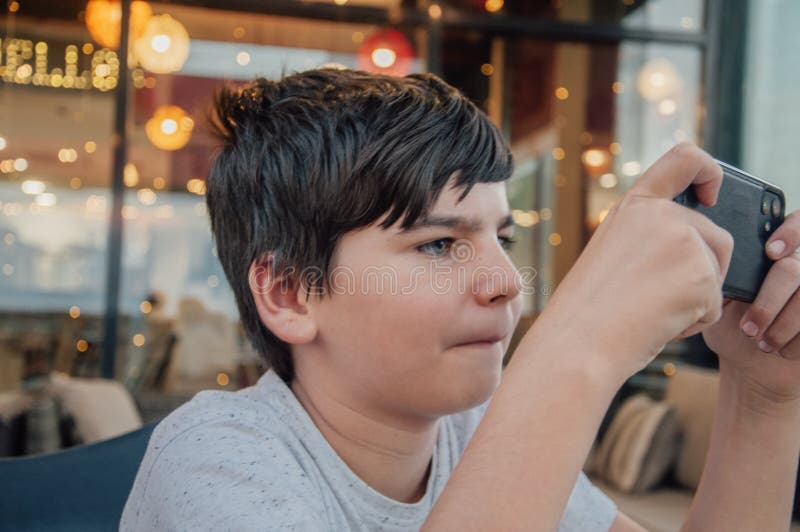 Portrait of Young Boy Playing Mobile Phone Games in a Bar, with ...