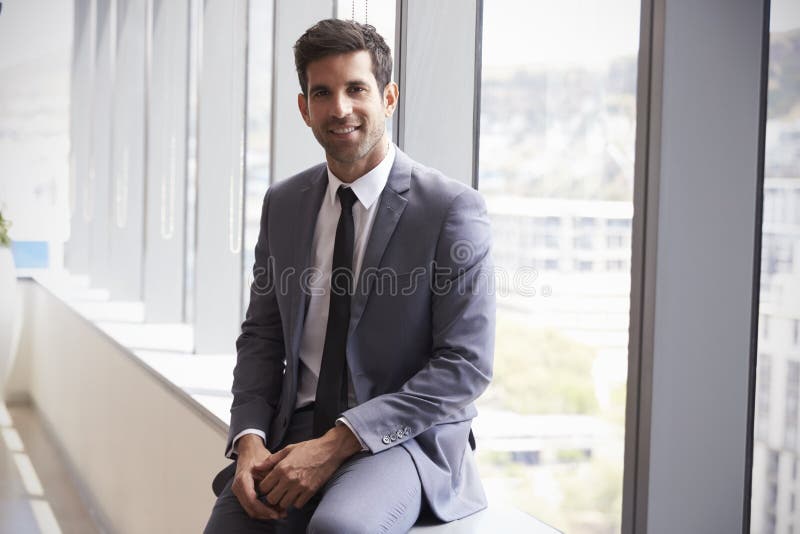 Portrait of Young Businessman Sitting by Window in Office Stock Photo ...