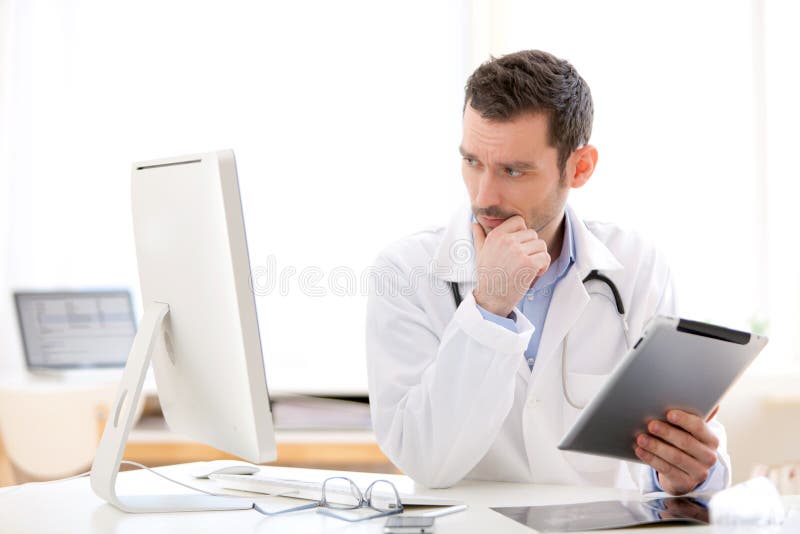 Doctor in Scrubs Using Computer at Hospital Desk Stock Image - Image of ...