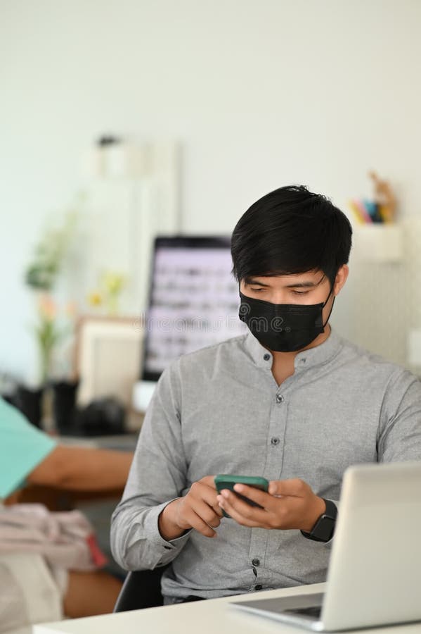 Portrait of a Young Man with Face Mask is Using Mobile Phone. Stock ...