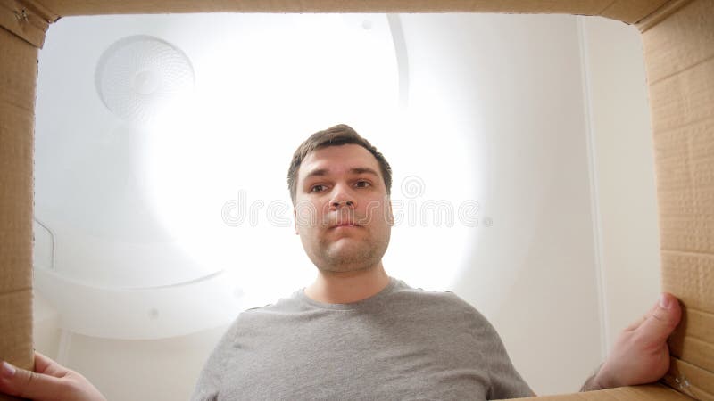 Portrait of Young Man Looking Inside Cardboard Box with Parcel or ...