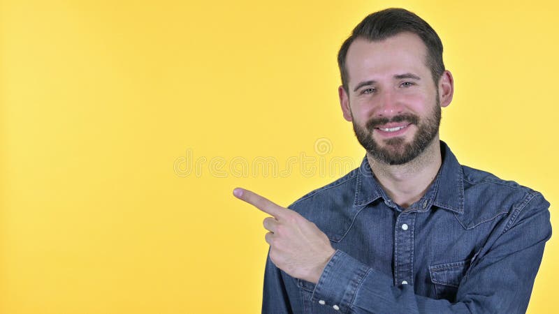 The Portrait of Young Man Pointing at Product, Yellow Background Stock ...