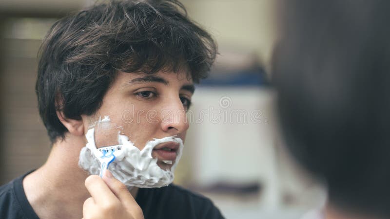 Young Man Shaving Beard in Front of Mirror Stock Image - Image of ...