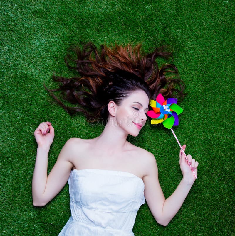 Portrait Of A Young Redhead Woman With Pinwheel Lying Down On Gr Stock