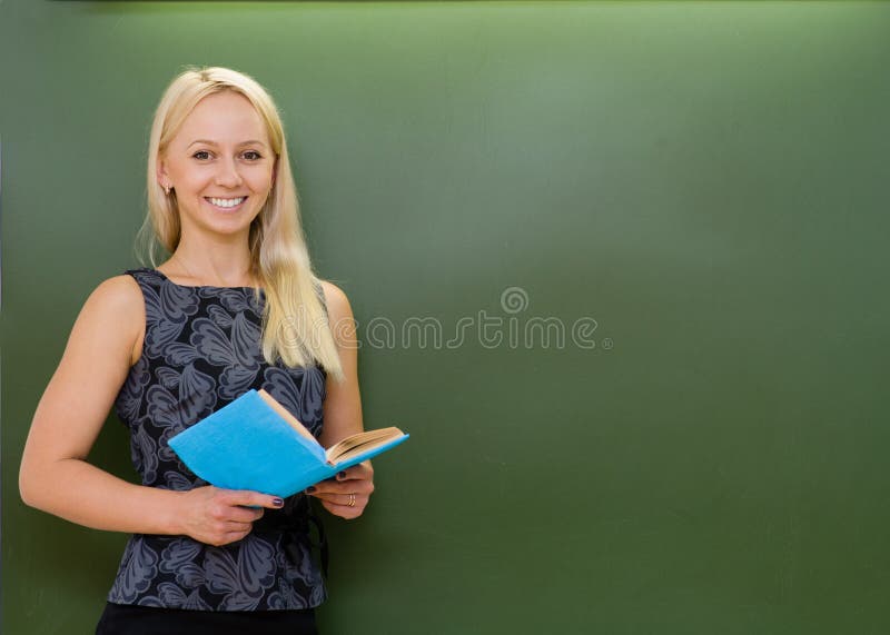 Confident Young Female Teacher In Front Of Chalkboard Stock Image