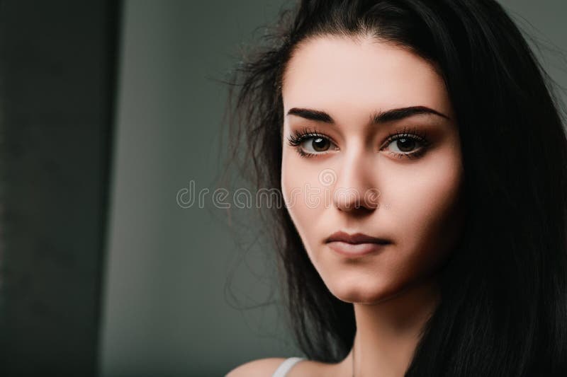 Stern Beautiful Young Woman With Long Black Hair Posing On Dark