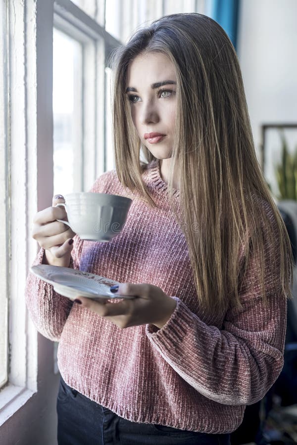 Portrait of a Young Woman Standing Next To a Window while Holding a Cup ...
