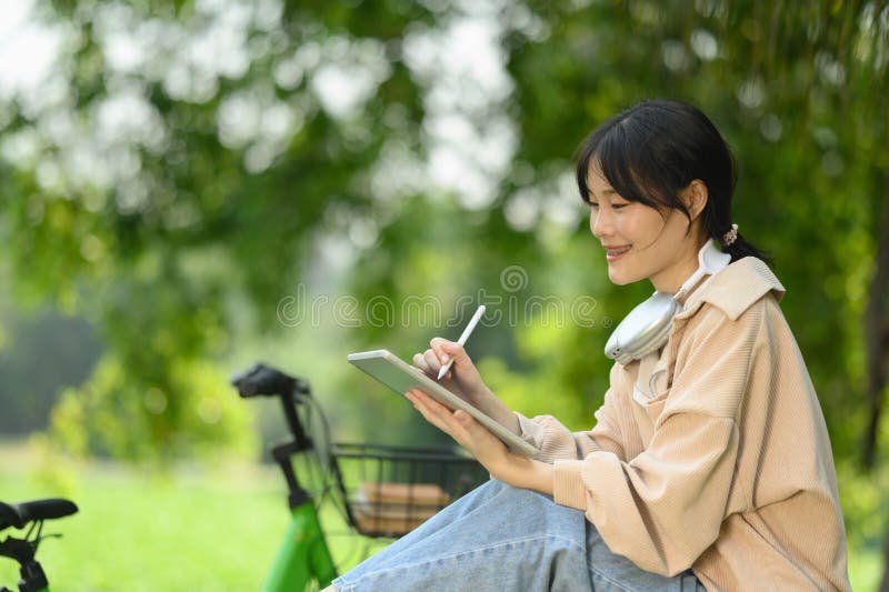 Positive Asian Student Girl Sitting on Park Bench and Using Digital ...