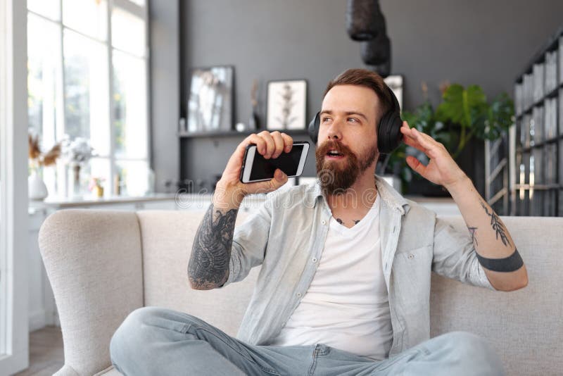 Positive Bearded Man Listening Music With Headphones While Sitting On