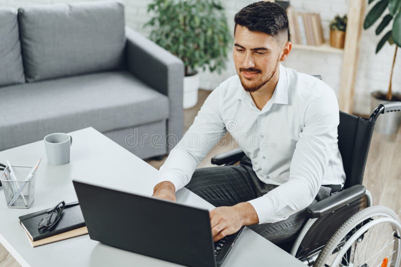 Positive Disabled Young Man in Wheelchair Working in Office Stock Image ...