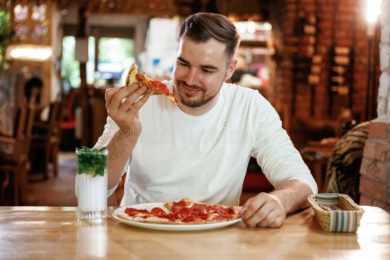Positive, Enjoying. Man is Sitting in the Restaurant and Eating a Pizza ...