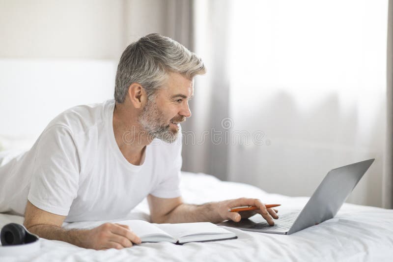 Positive Middle Aged Man Using Laptop, Taking Notes in Notepad Stock ...