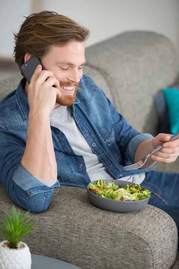 Positive Handsome Man Eating Salad while Having Phone-conversation ...