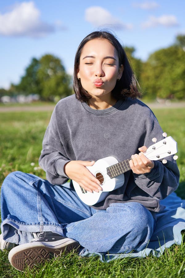 Positive Hipster Asian Girl Playing Ukulele And Making Faces Singing