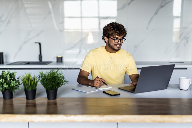 Positive Indian Man Looking for Job Online, Sitting at Table, Using ...