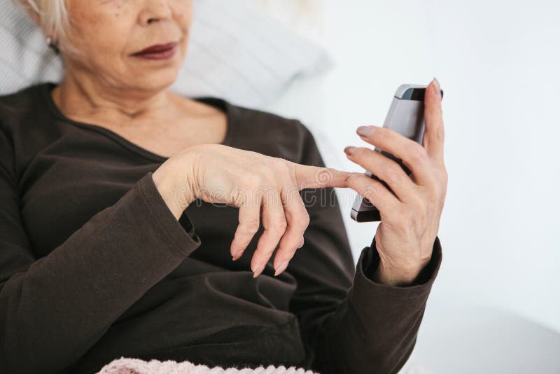 A Positive Modern Elderly Woman is Holding a Cell Phone and is Using it ...