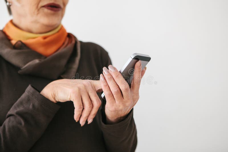 A Positive Modern Elderly Woman is Holding a Cell Phone and is Using it ...