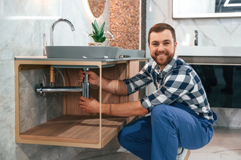 Positive Plumber in Blue Uniform is at Work in the Bathroom Stock Photo ...