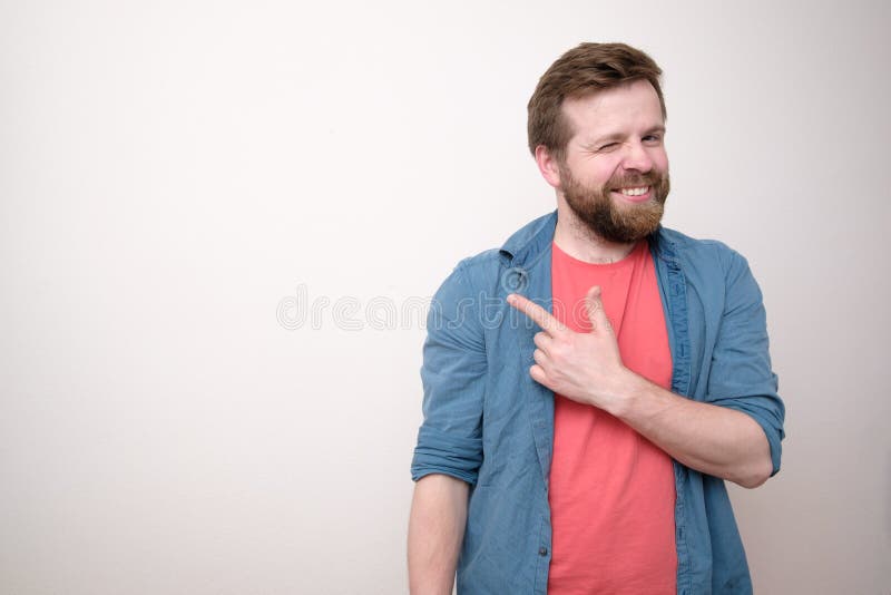 Positive, Smiling Man Points His Index Finger To the Side and Looks ...