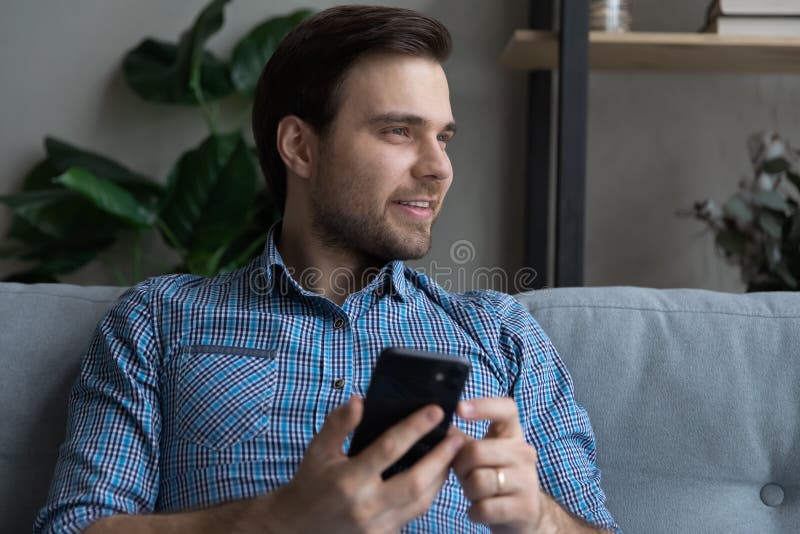 Positive Thoughtful Cellphone User Sitting on Sofa at Home Stock Image ...