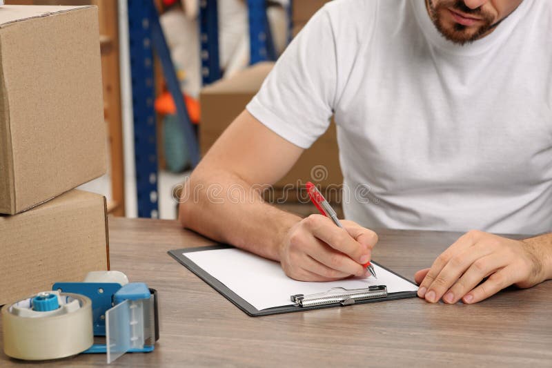 Post Office Worker with Clipboard and Parcels at Counter Indoors ...