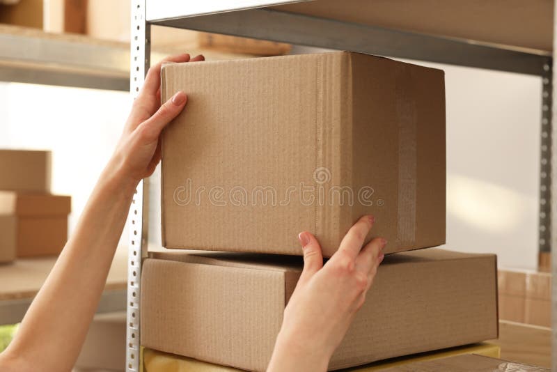 Post Office Worker Putting Box on Parcel Rack with Parcels Indoors ...