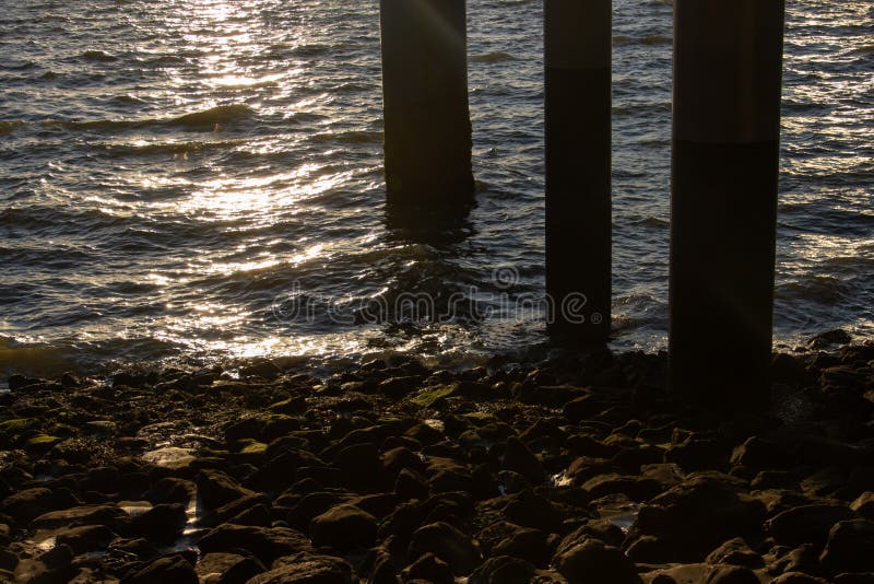 Posts Under a Pier and Waves Reflecting the Sun during Sunset Stock ...