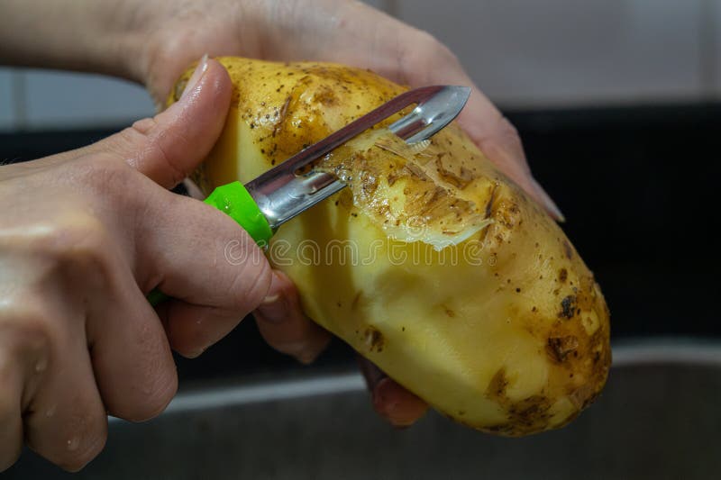 Potapo Peeling. Hands Peeling Raw Potato with Vegetable Peeler in the ...