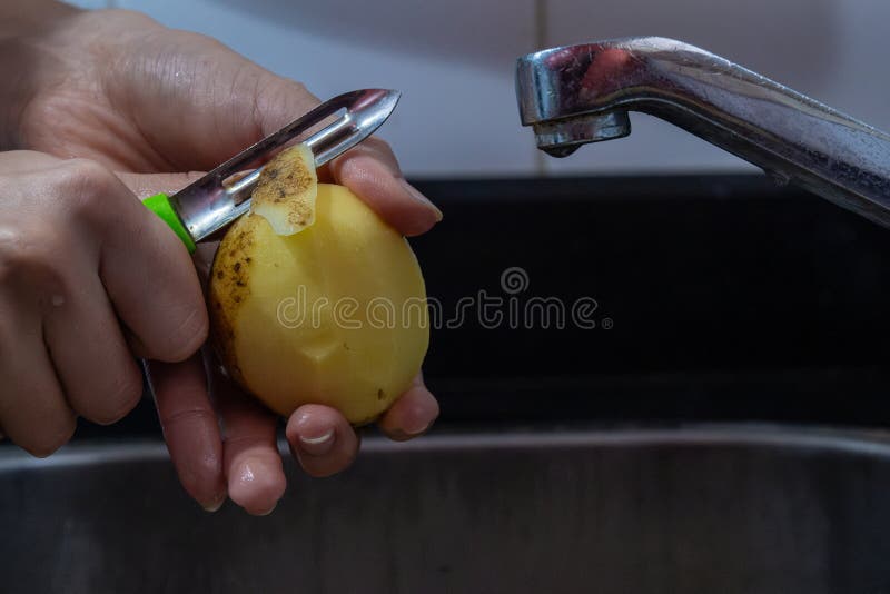 Potapo Peeling. Hands Peeling Raw Potato with Vegetable Peeler in the ...