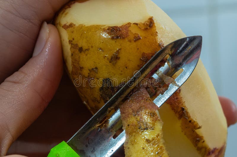Potapo Peeling. Hands Peeling Raw Potato with Vegetable Peeler in the ...